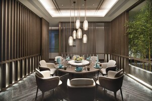 Uma área de refeições moderna com uma mesa redonda, cadeiras e luminárias pendentes.