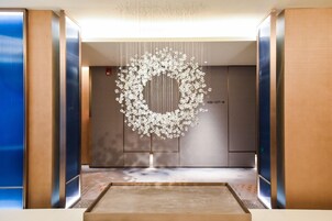 Um elevador com design moderno, apresentando uma luminária pendente única e um painel digital com os números dos andares.