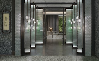 Uma entrada moderna com painéis de vidro jateado, luminárias esféricas pendentes e um vaso decorativo central.