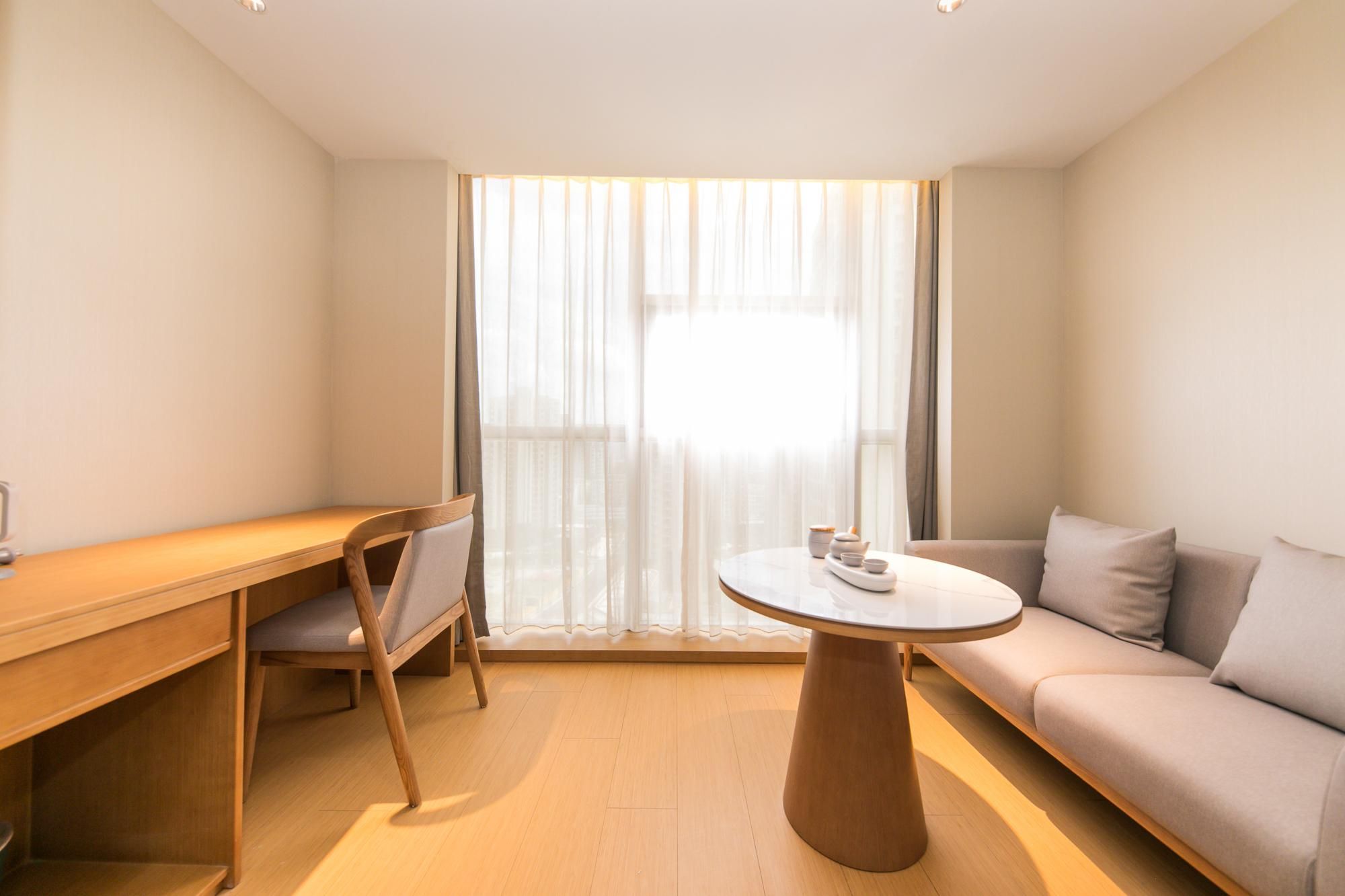 Uma sala de estar moderna com uma escrivaninha de madeira, uma mesa redonda e um sofá.