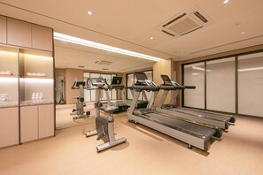 Uma academia moderna com esteiras, bicicletas ergométricas e um espelho.