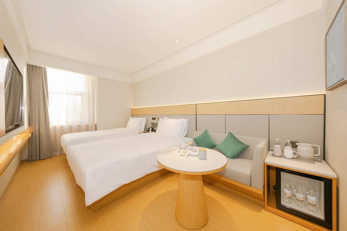 Quarto de hotel com uma cama grande, uma mesa redonda, um sofá e um minibar.