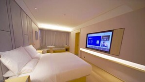 Quarto de hotel moderno com uma cama grande, uma televisão na parede e uma mesinha de cabeceira.