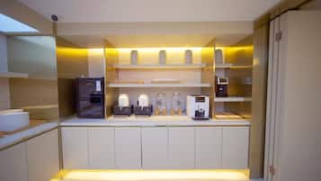 Uma cozinha compacta moderna com cafeteira, dispenser de água e micro-ondas.