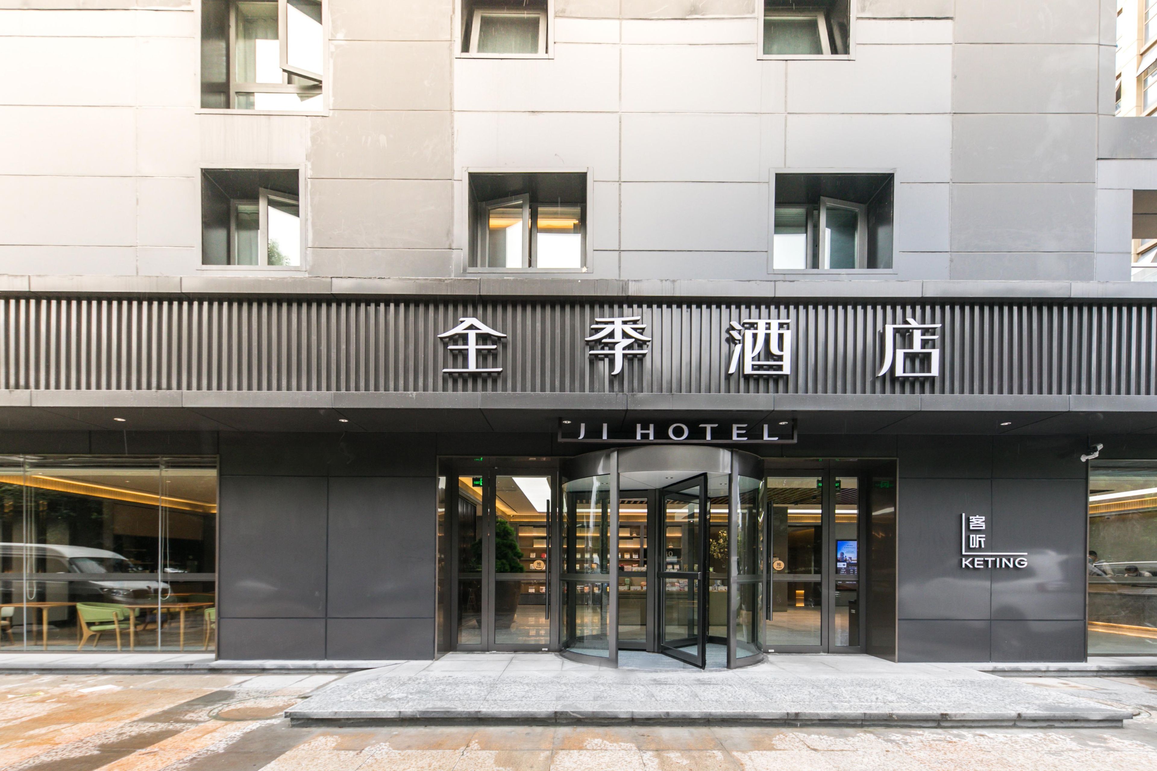 Entrada de hotel com porta giratória, placa com caracteres chineses e logotipo 'KETING'.