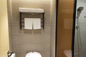 Um banheiro com vaso sanitário, porta-toalhas com toalhas e chuveiro.