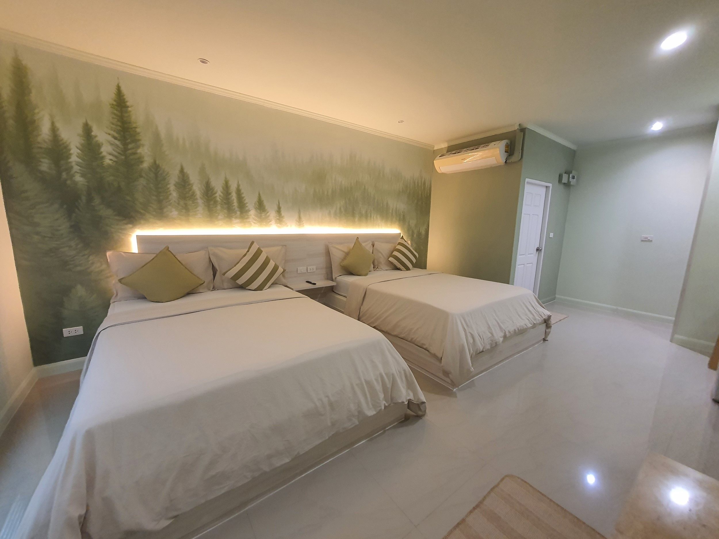 Quarto com duas camas, um mural na parede e aparelho de ar condicionado.