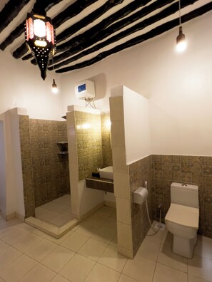 Uma casa de banho com chuveiro, sanita e lavatório.