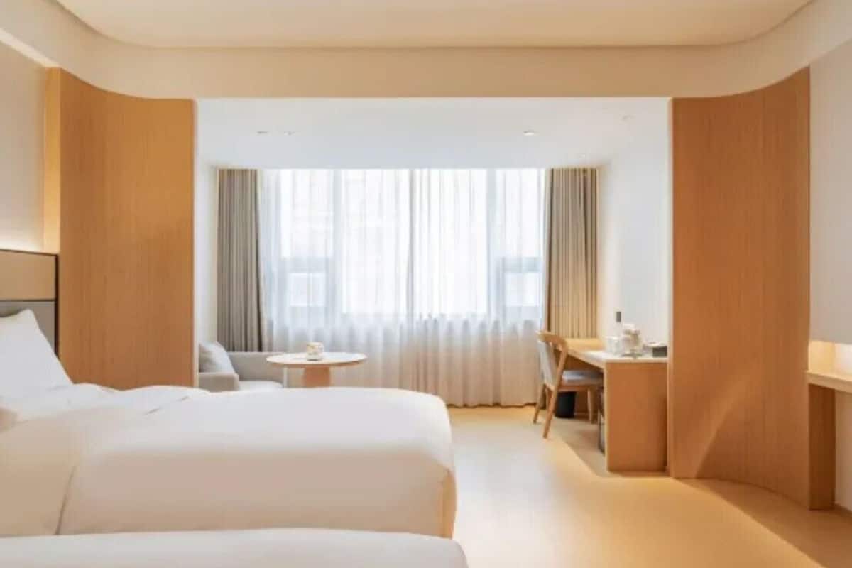 Quarto de hotel com duas camas, uma escrivaninha e uma cadeira.