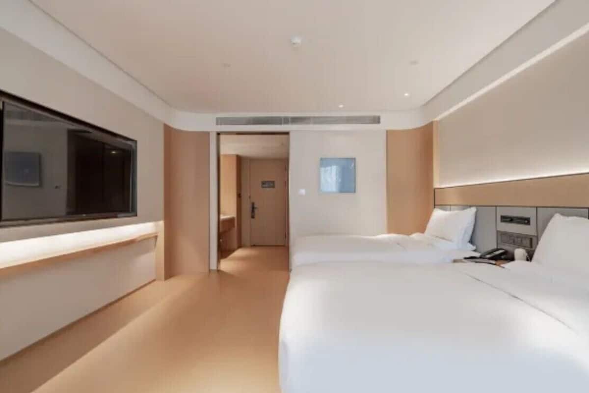 Quarto de hotel com uma cama grande, televisão de tela plana na parede e mesa de cabeceira com abajur.