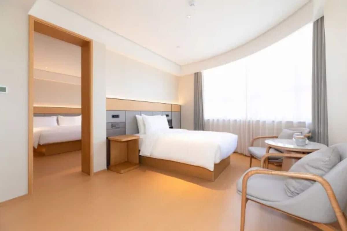 Quarto de hotel com cama, mesa de cabeceira, cadeira e uma pequena mesa com uma chávena.
