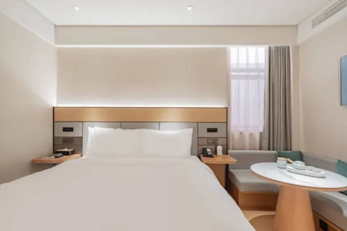 Quarto de hotel com uma cama grande, mesas de cabeceira, uma mesa redonda e um espaço de estar.