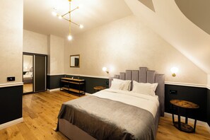 Quarto com cama, mesas de cabeceira, espelho e luminária no teto.