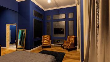 Quarto com uma cama grande, duas poltronas, televisão e lareira.