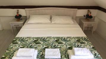 Quarto de hotel com uma cama, duas mesas de cabeceira e uma mesinha de apoio com abajur.