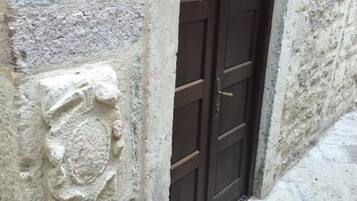 Um edifício de pedra com uma porta de madeira escura e um tapete vermelho pequeno na entrada.
