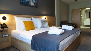 Quarto de hotel com cama, mesa de cabeceira e telefone.