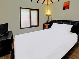 Quarto de hotel com cama, televisão, mesa de cabeceira, abajur, janela e uma obra de arte na parede.