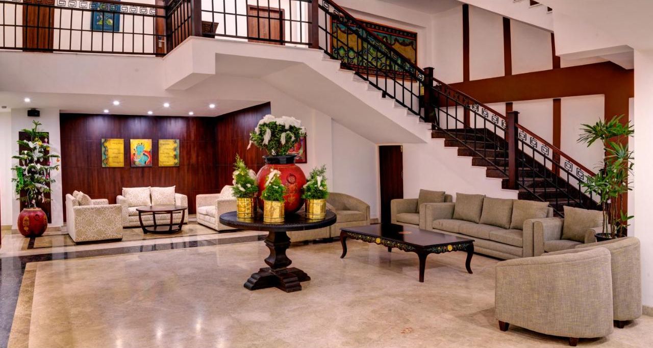 Um hall amplo com escada, sofás, mesa de centro e vasos decorativos.