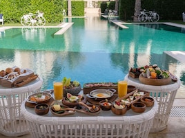 Um buffet de café da manhã com diversos alimentos e bebidas à beira da piscina.