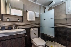 Uma casa de banho moderna com lavatório, sanita e chuveiro.