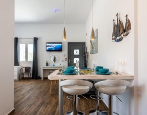 Uma cozinha moderna com área de refeições, piso de madeira e televisão presa na parede.