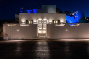 Um edifício moderno com uma escadaria que leva a uma porta, rodeado por paredes com iluminação integrada.