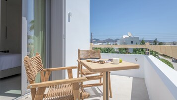 Uma varanda com mobiliário de vime, uma mesa e um copo de leite.
