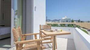 Uma varanda com mobiliário de vime, uma mesa e um copo de leite.