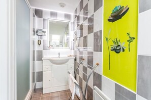 Casa de banho com lavatório branco, espelho e porta-toalhas.