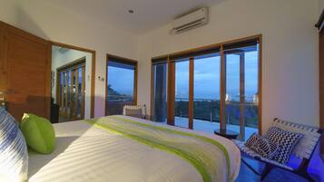 Quarto com uma cama grande, varanda com vista e ar condicionado.