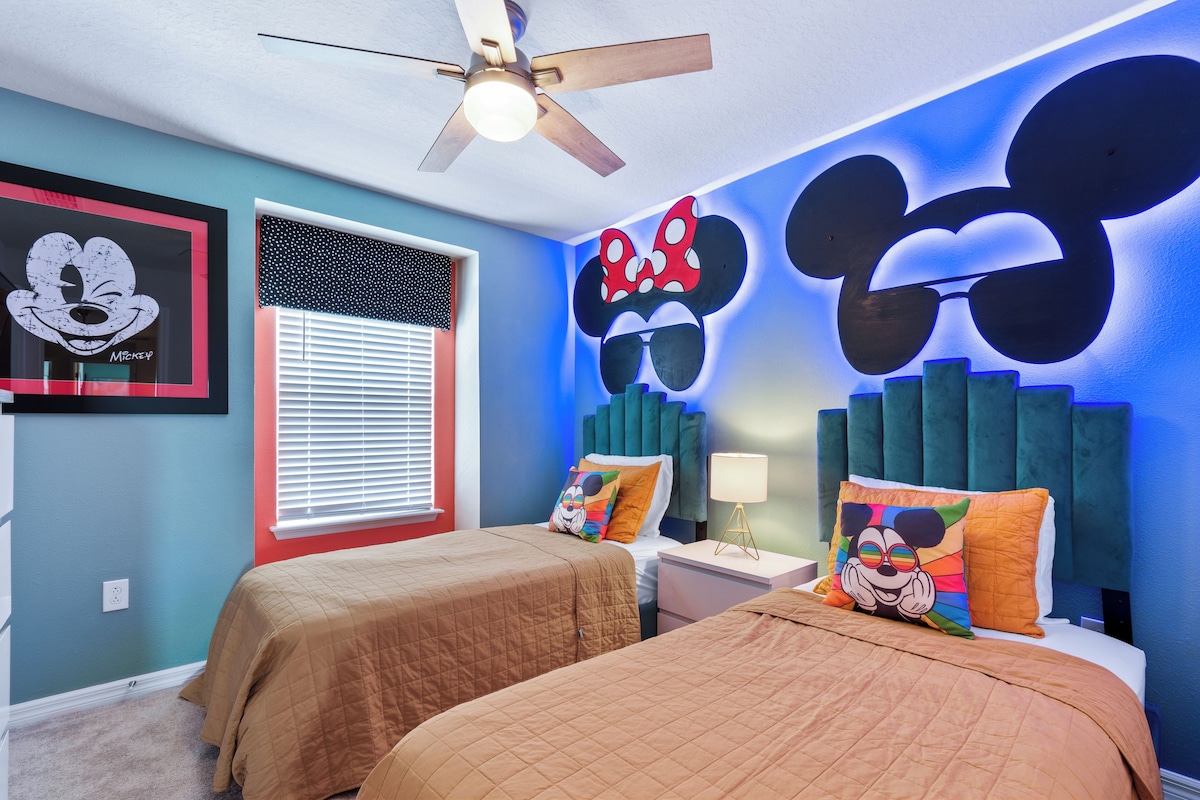 Quarto com duas camas, ventilador no teto e decoração temática do Mickey Mouse.