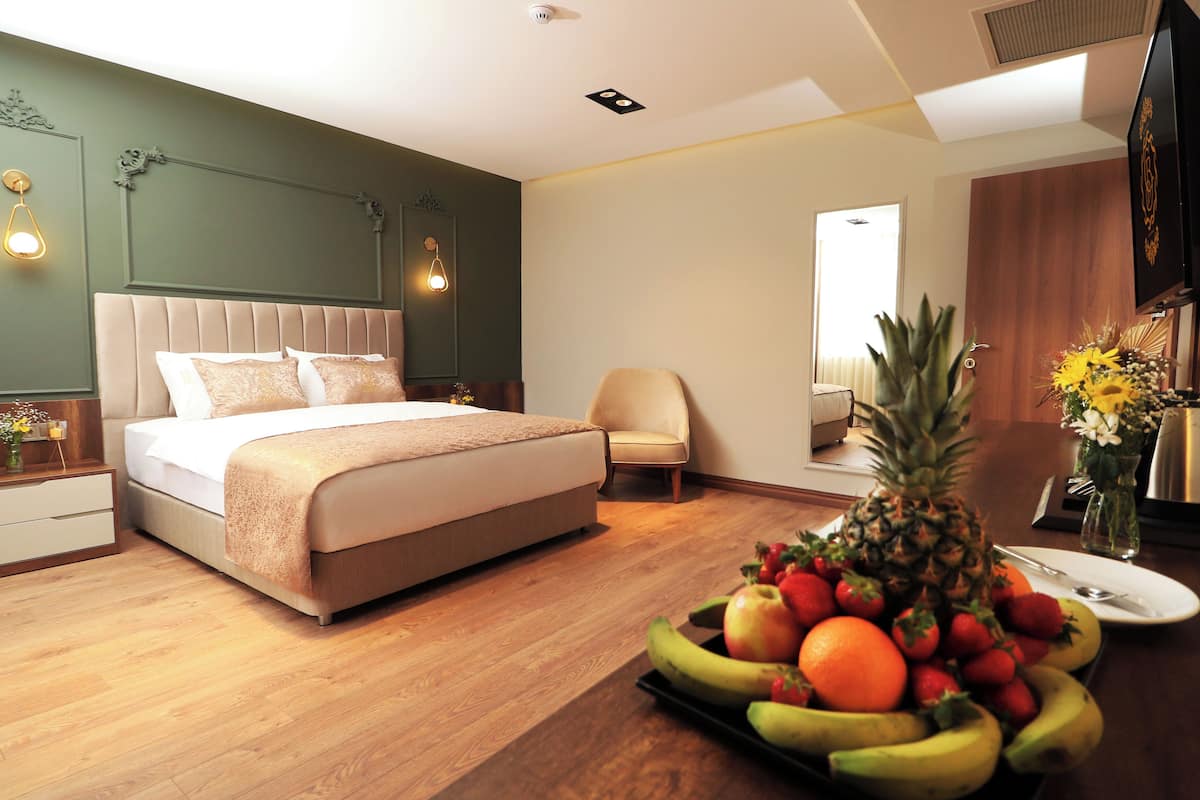 Um quarto moderno com uma cama, uma cadeira, uma fruteira e uma televisão.
