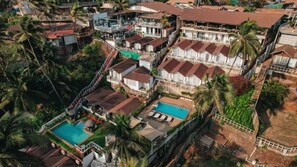Um hotel com vários andares, piscina, varandas e vegetação exuberante.