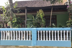 Um edifício com telhado telhado, corrimão azul e diversas plantas.