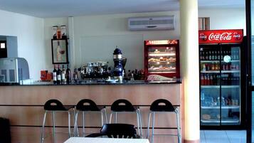 Uma área de bar com geladeira, prateleiras cheias de garrafas e uma máquina de refrigerador Coca-Cola.
