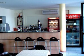 Uma área de bar com geladeira, prateleiras cheias de garrafas e uma máquina de refrigerador Coca-Cola.