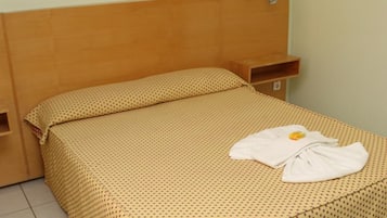 Uma cama de solteiro com cabeceira, mesa de cabeceira e luminária na parede.