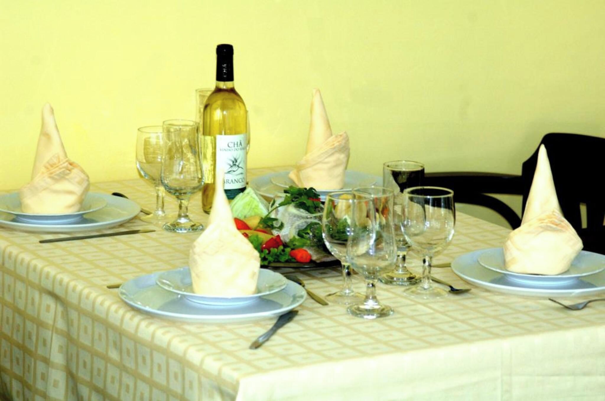 Mesa de jantar posta com pratos, guardanapos, copos de vinho e uma garrafa de vinho.