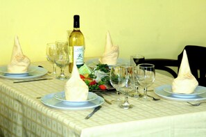 Mesa de jantar posta com pratos, guardanapos, copos de vinho e uma garrafa de vinho.