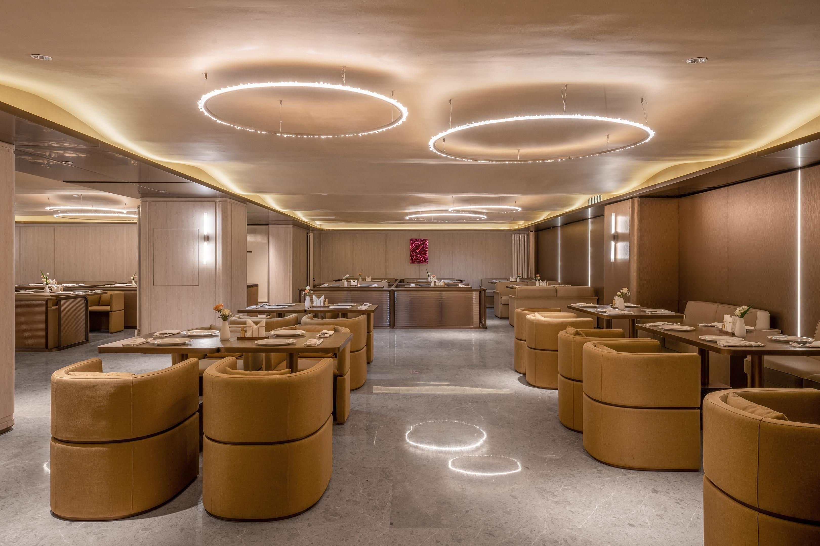 Um lobby de hotel moderno com mesas redondas, assentos acolchoados e um balcão de recepção central.