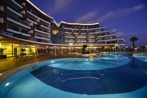 Um hotel moderno com uma piscina grande, várias varandas e áreas de estar ao ar livre.