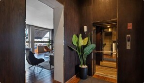 Decoração moderna com piso de madeira, planta em vaso e elevador.