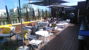 Bar no terraço com área externa, incluindo cadeiras e mesas sob guarda-sóis.