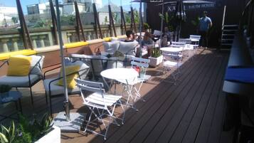 Bar no terraço com área externa, incluindo cadeiras e mesas sob guarda-sóis.