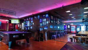 Uma sala de bilhar com várias mesas, cadeiras e uma mesa de sinuca.