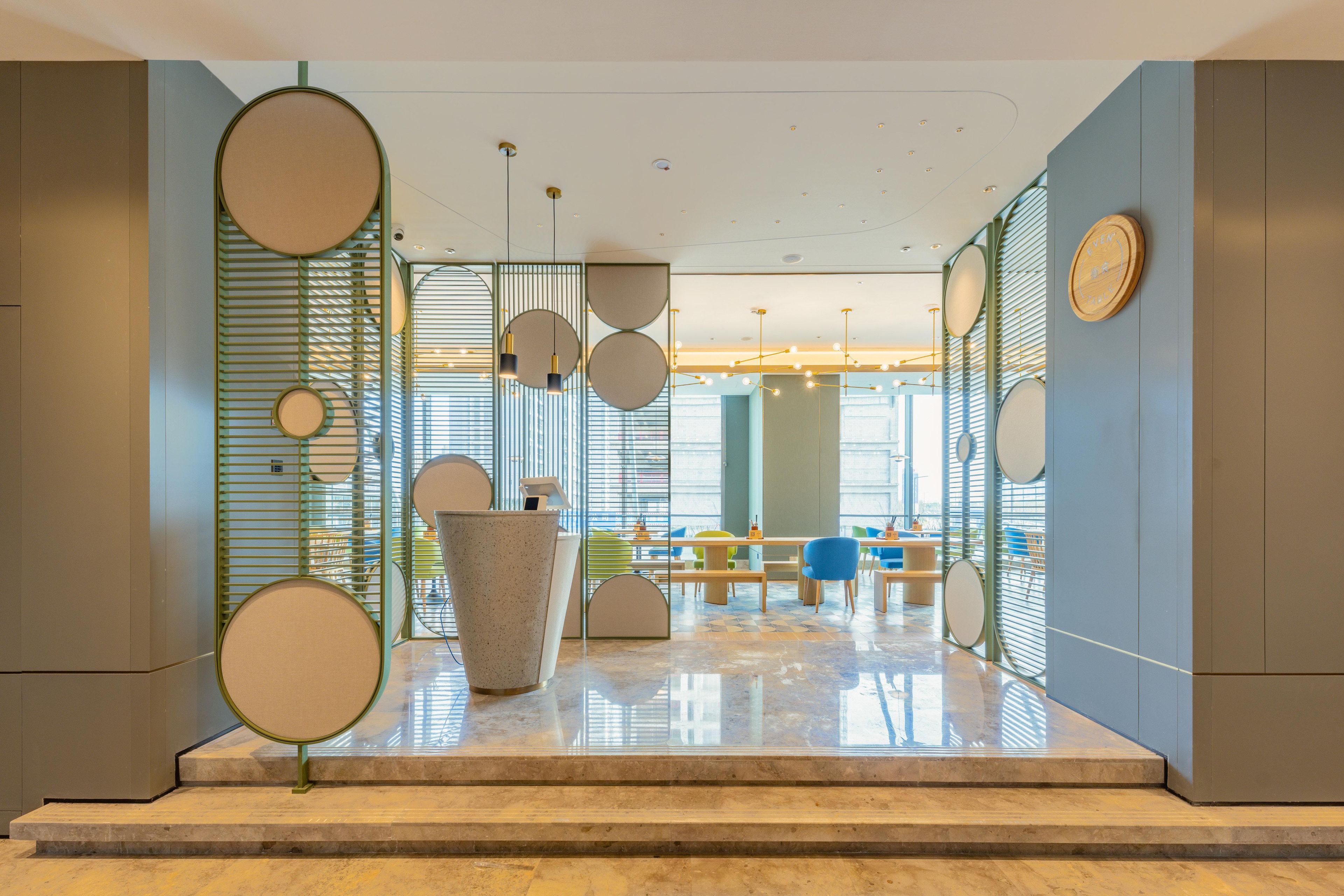 Um interior moderno com balcão de recepção, área de estar e grandes janelas.