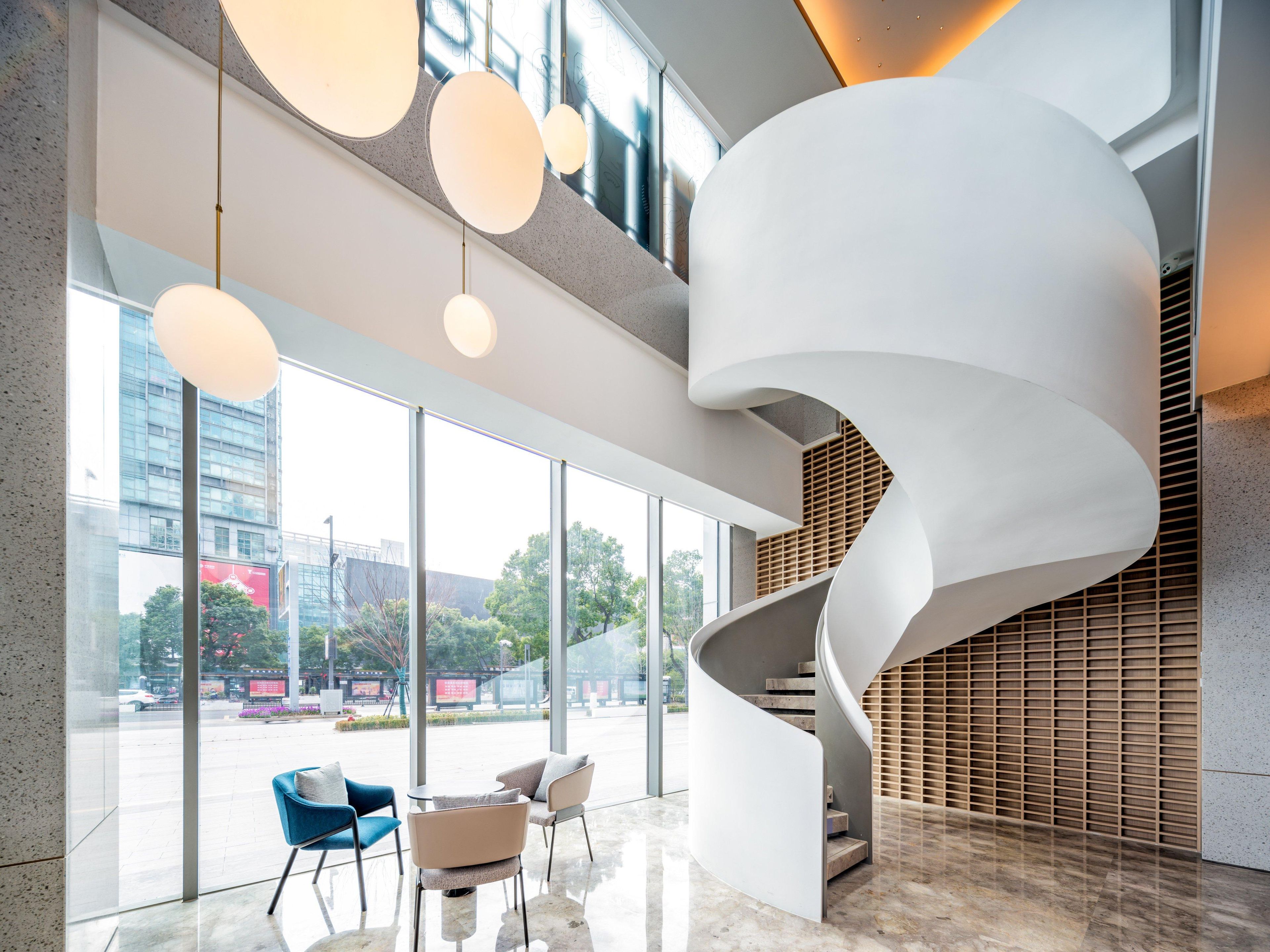 Um interior moderno com uma escada em espiral, janelas amplas e móveis contemporâneos.