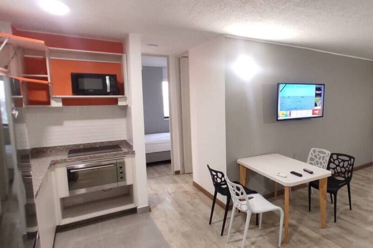 Sala moderna com mesa de jantar, cadeiras, televisão e uma janela grande.