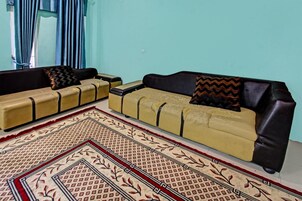 Uma sala de estar com dois sofás, um tapete estampado e uma janela com cortinas.